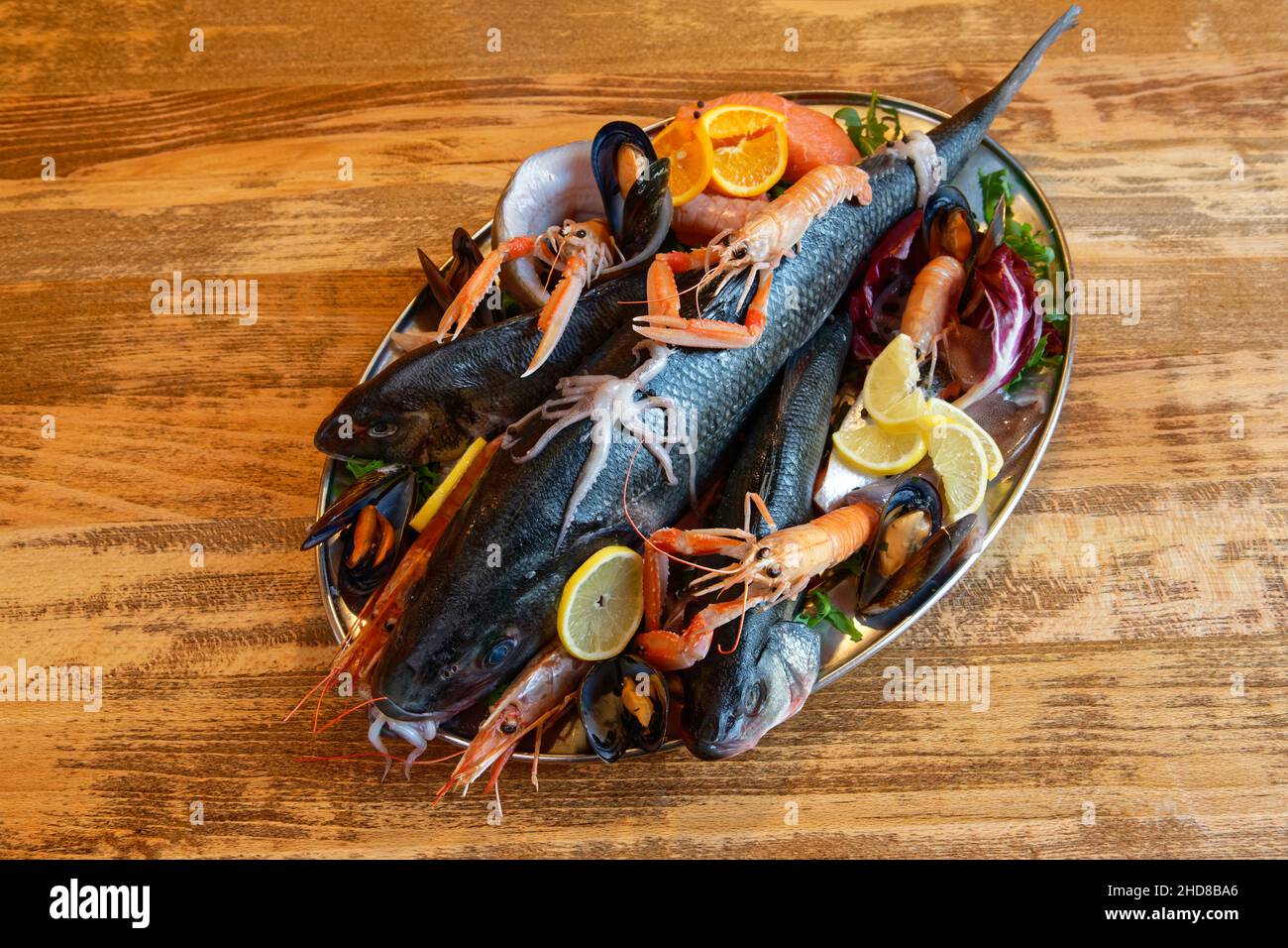 A platter of raw whole fish and seafood for presentation on a wooden ...