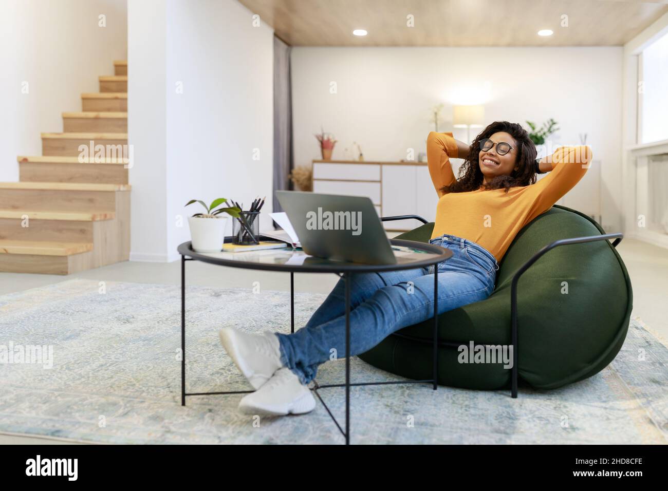 Smiling black woman leaning back sitting at desk Stock Photo - Alamy