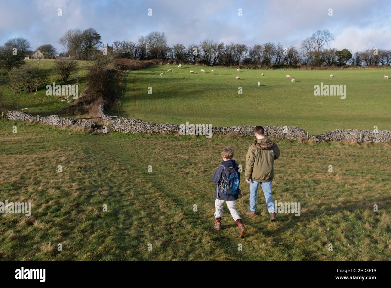 A young 12 year-old boy and his mid-20s cousin walk across a field ...