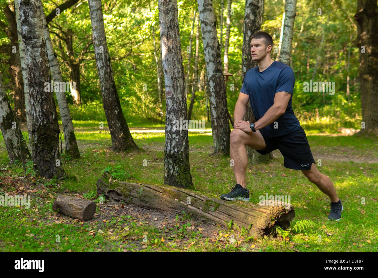 A young enduring athletic athlete is doing stretching in the forest ...