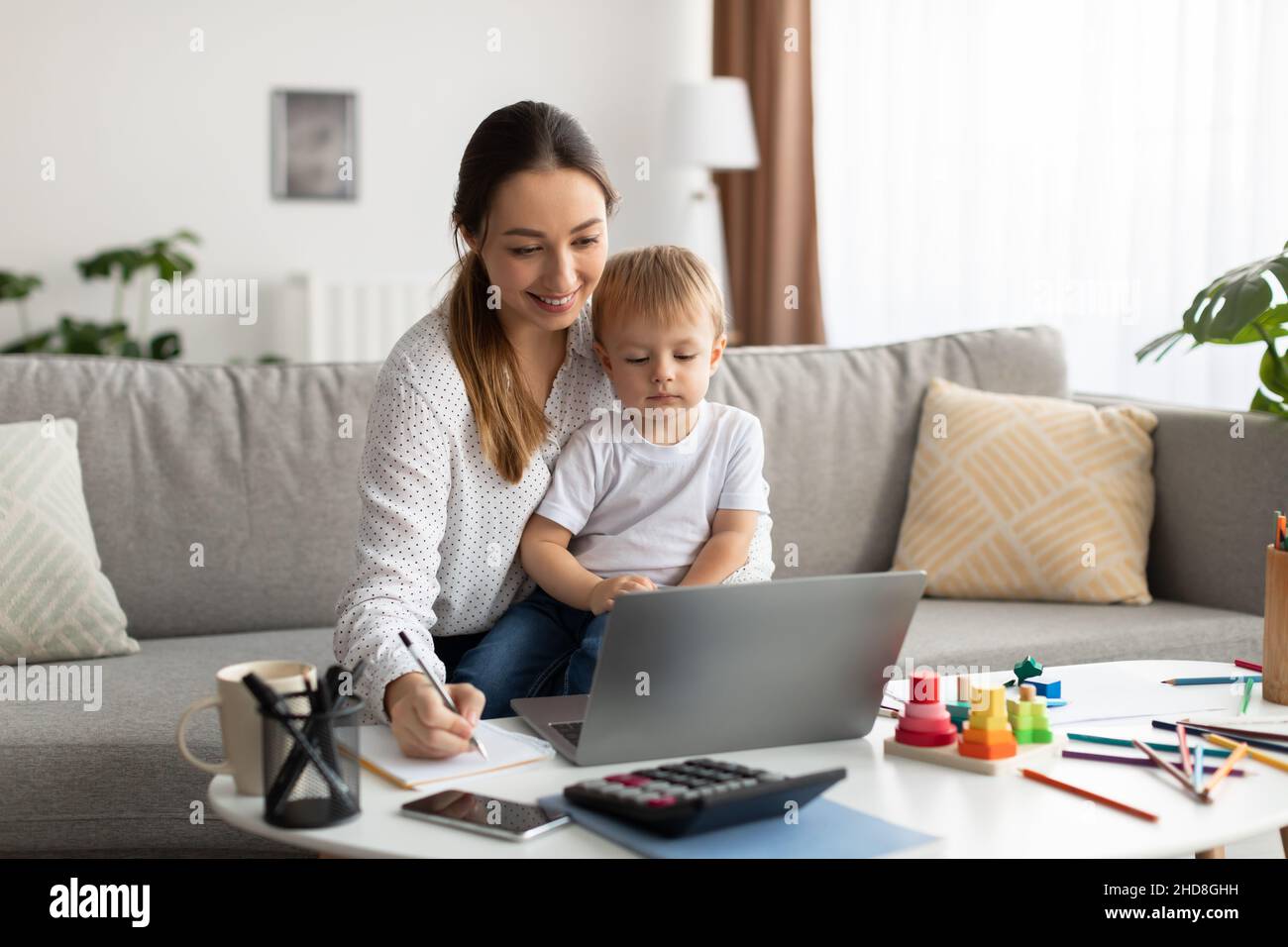 Online education. Young mother holding baby and studying with laptop ...