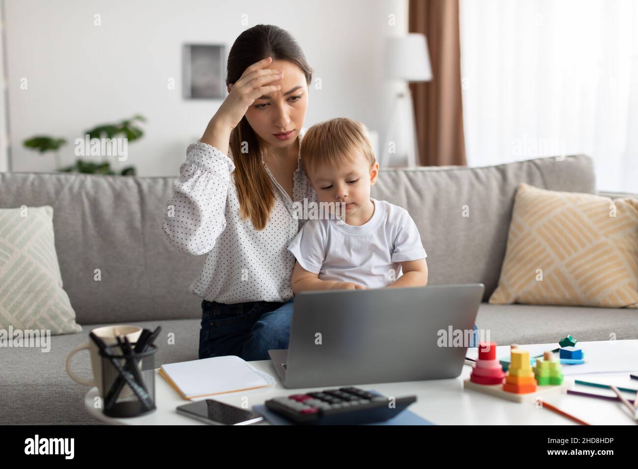 Remote work stress. Tired mother holding toddler son and looking at ...