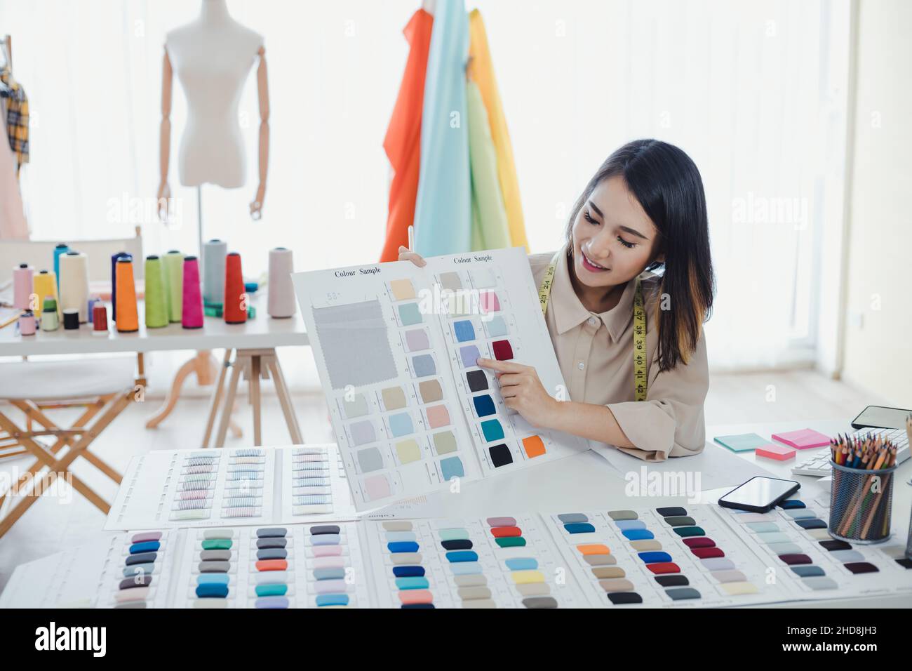 Asian woman designer are thinking and designing clothes for customers ...