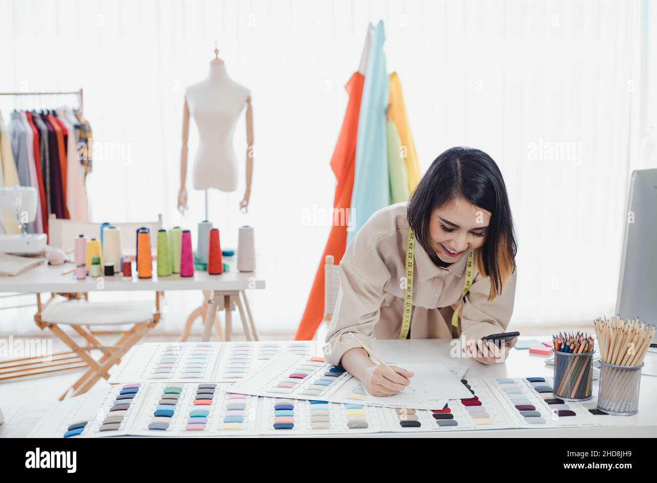 Asian woman designer are thinking and designing clothes for customers ...