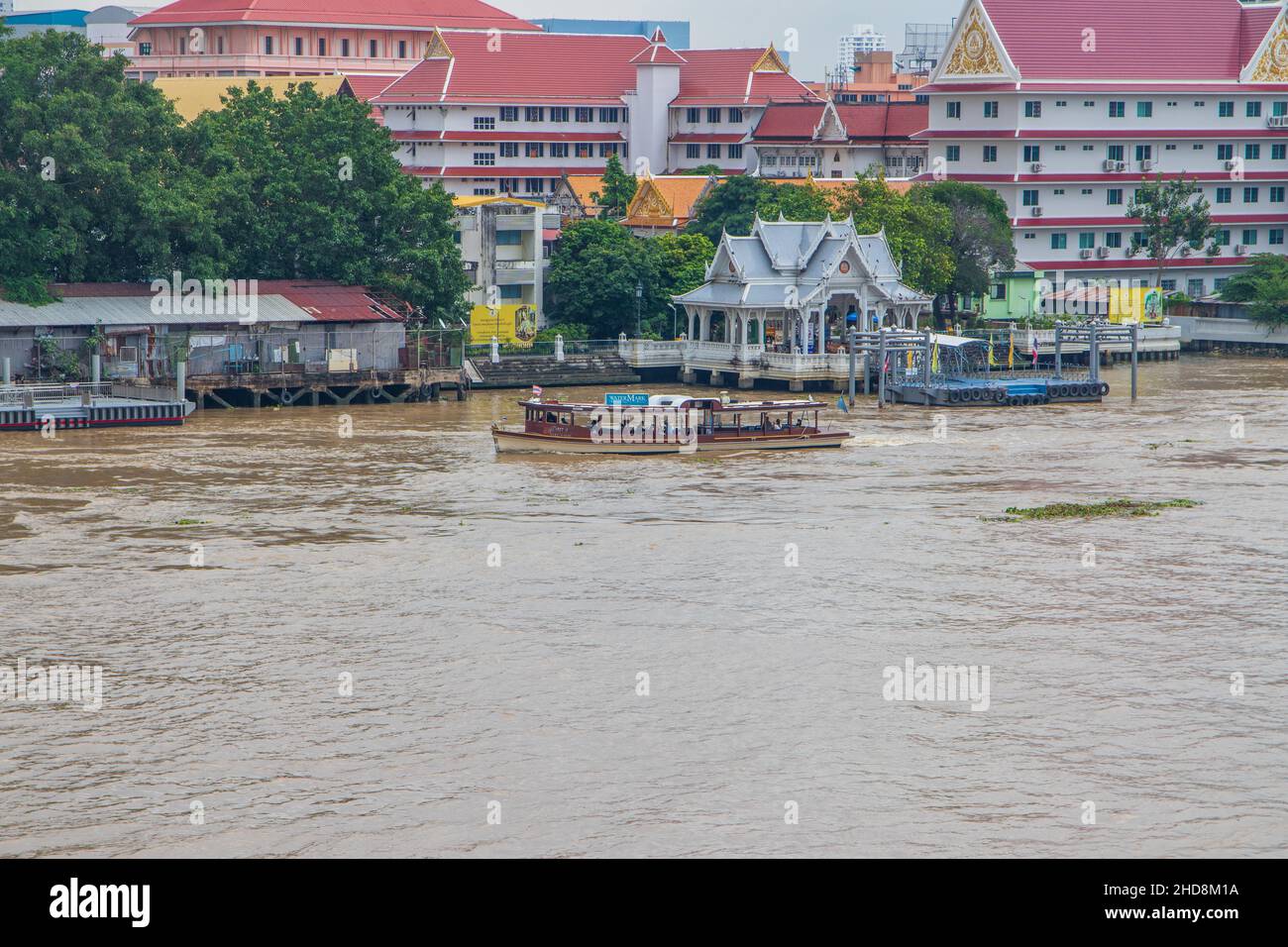 A ferry boat,a ferry pier, the Chao Phraya River and the cityscape of ...