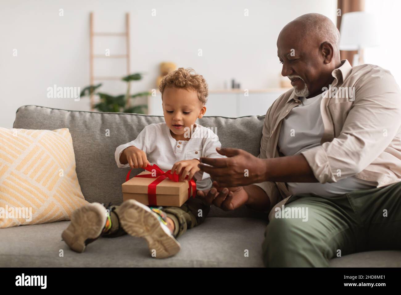 African American Grandpa Giving Wrapped Gift To Grandson At Home Stock ...