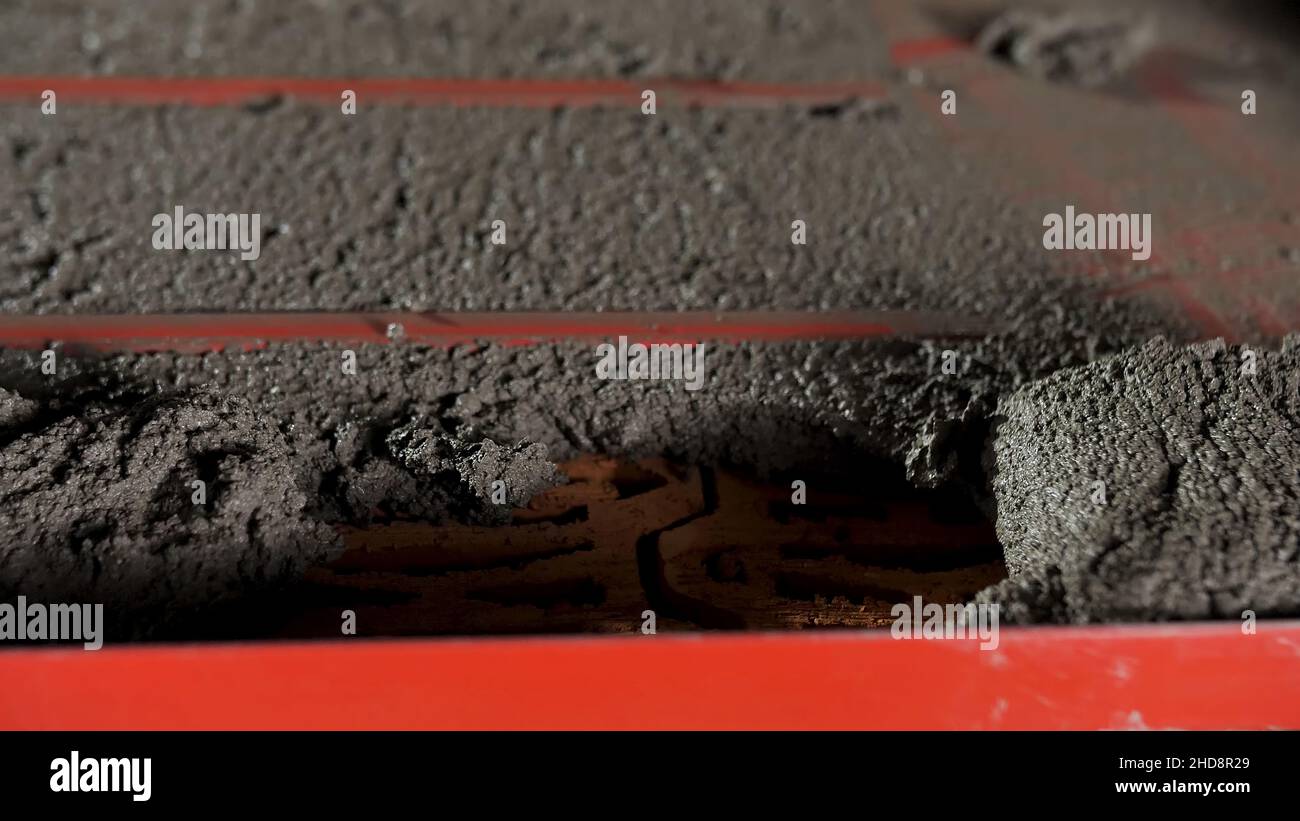 Bricklayer putting down another row of cement using a special red form ...