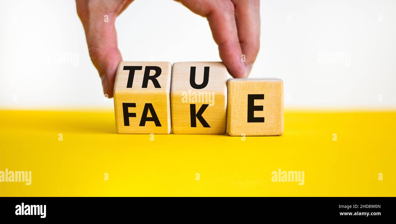 Fake or true symbol. Businessman turns wooden cubes and changes the ...