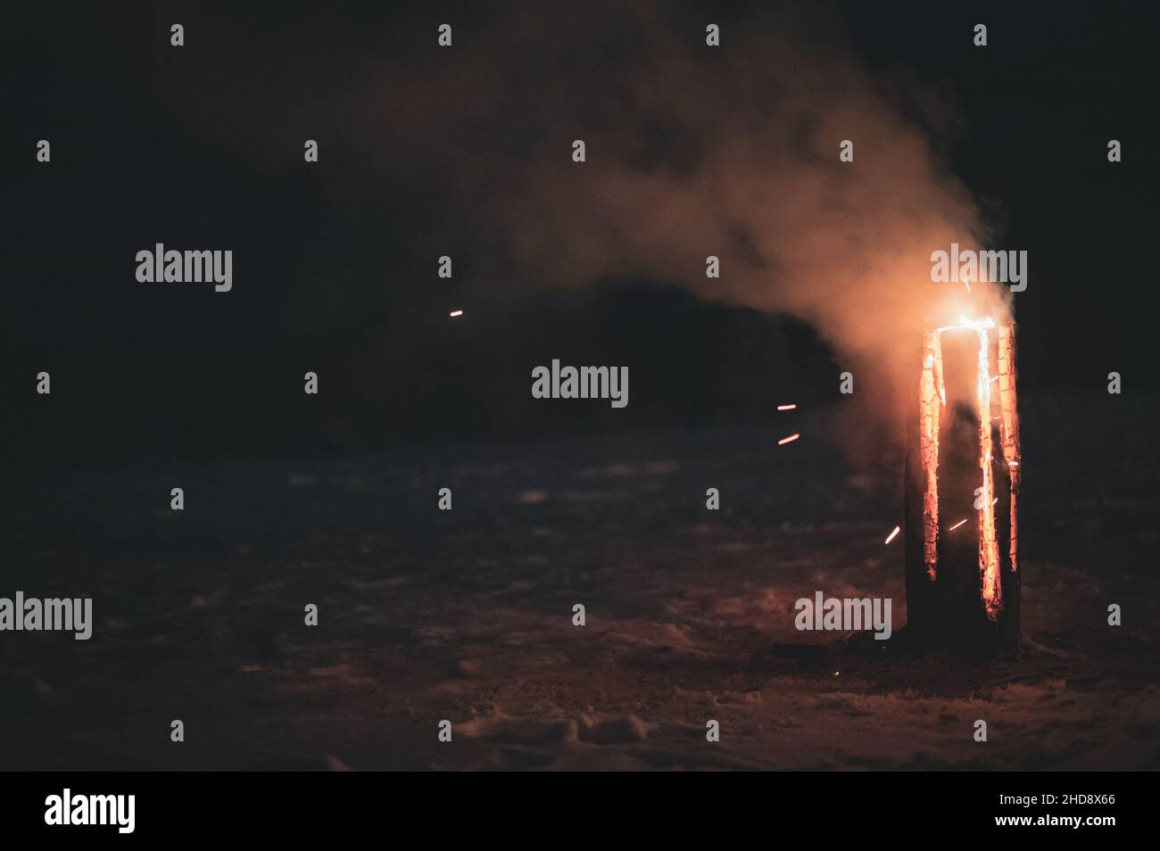 smoke from the flames of the fire and a wooden pole burning vertically ...