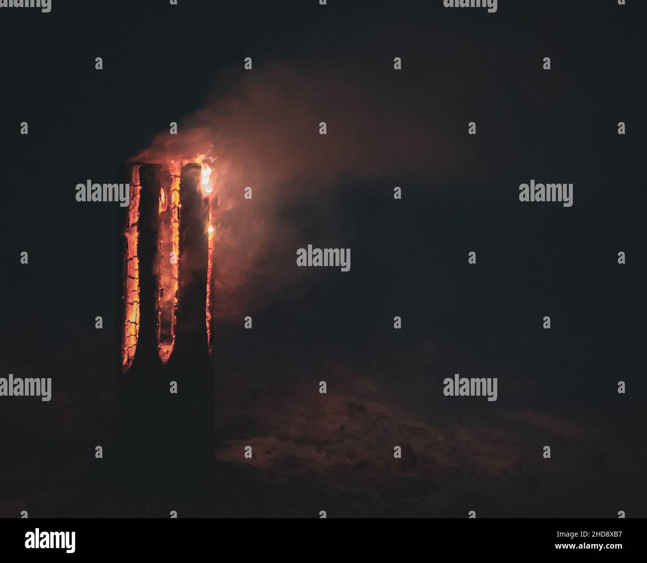 smoke from the flames of the fire and a wooden pole burning vertically ...