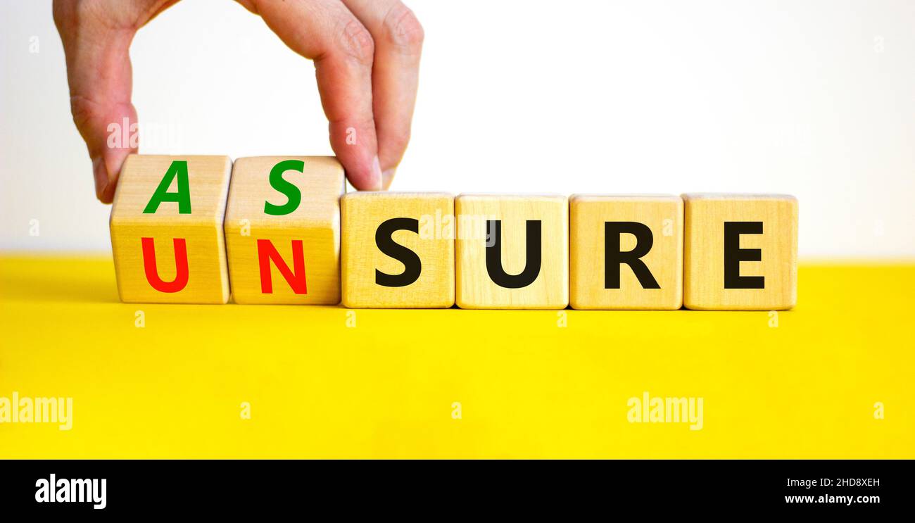 Assure or unsure symbol. Businessman turns wooden cubes and changes the ...