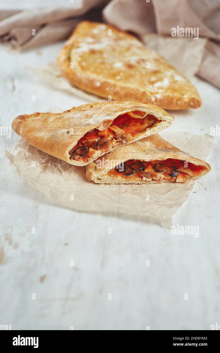 Delicious pizza calzone on a table with a light background Stock Photo ...