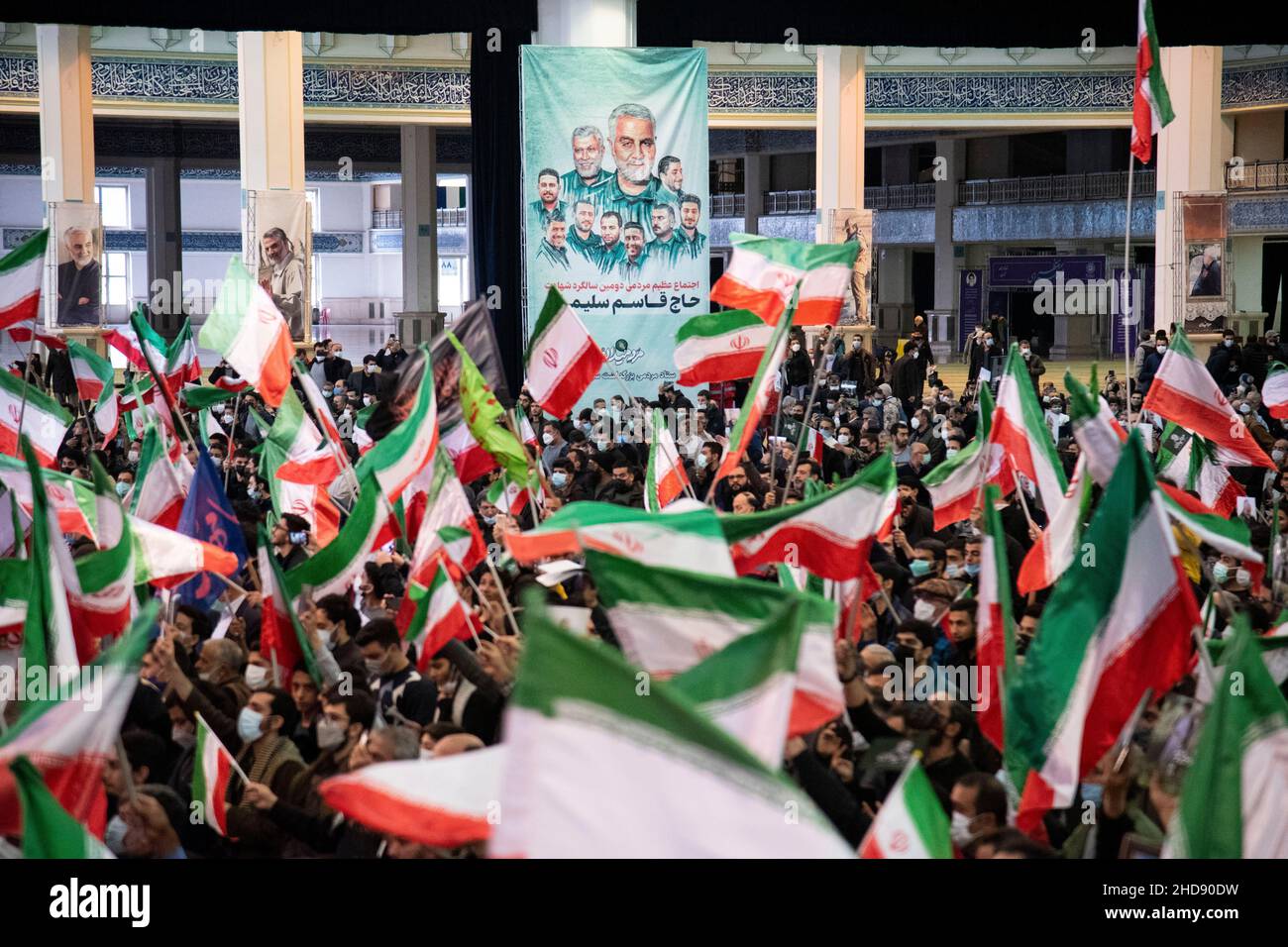 (1/3/2022) men wave the Iranian flag in front of a poster of the ...