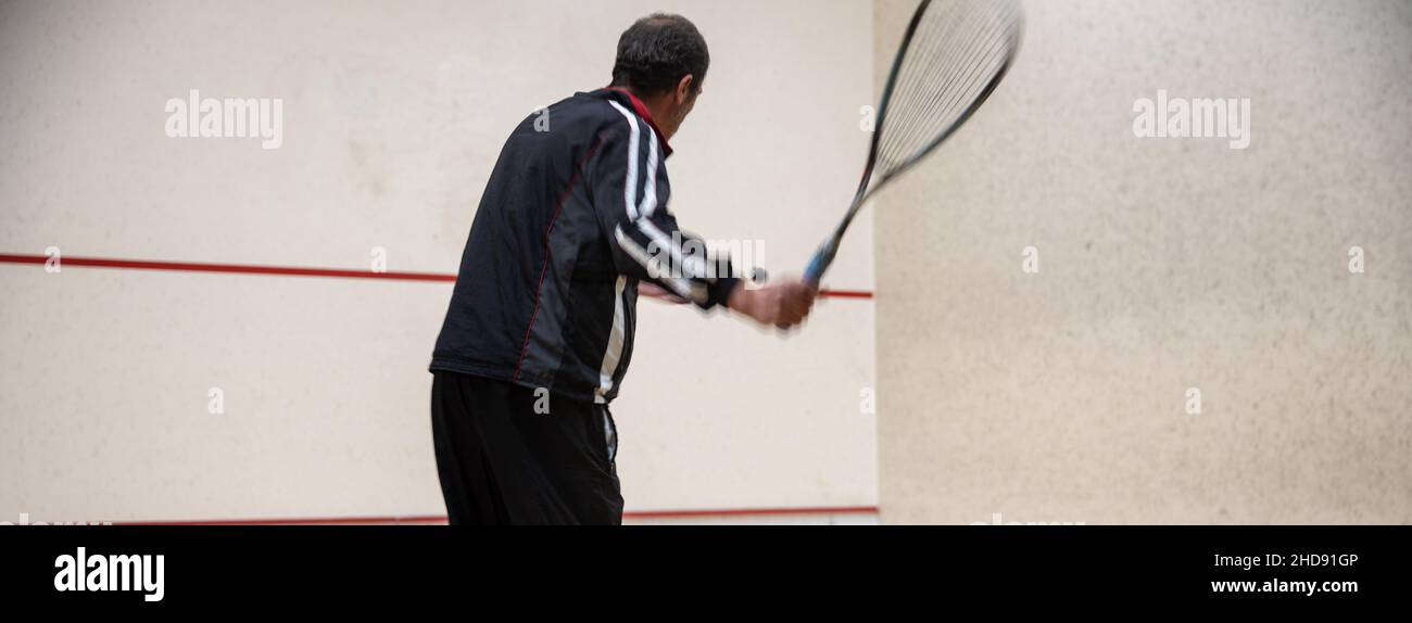 Squash player in action on a squash court (motion blurred image; color ...