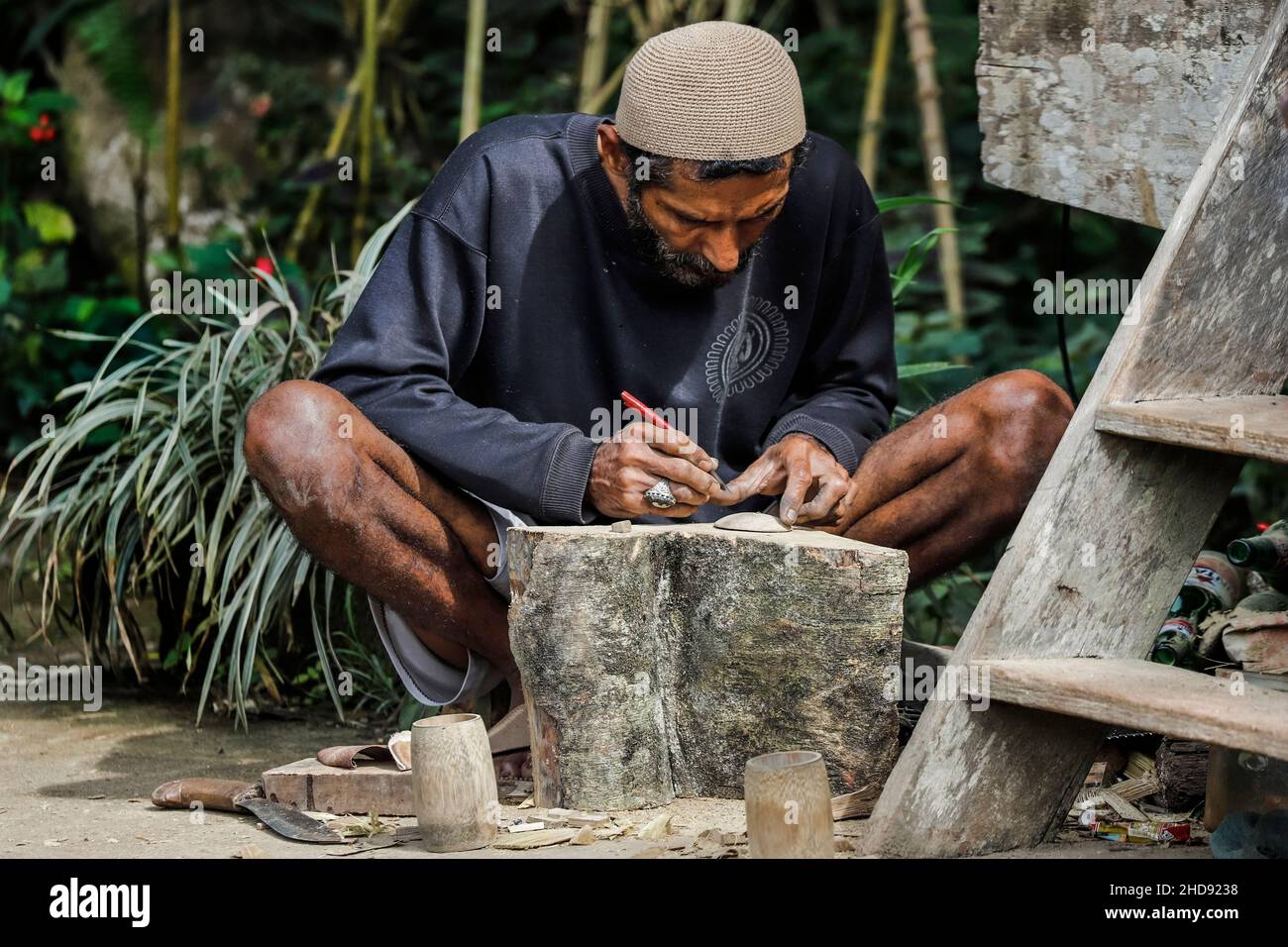 Torajan man carving bamboo items outside tonkonan family home near ...