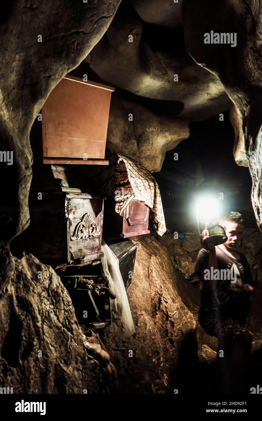 Young guide with lamp lighting coffins (erong) for tourists, at the ...