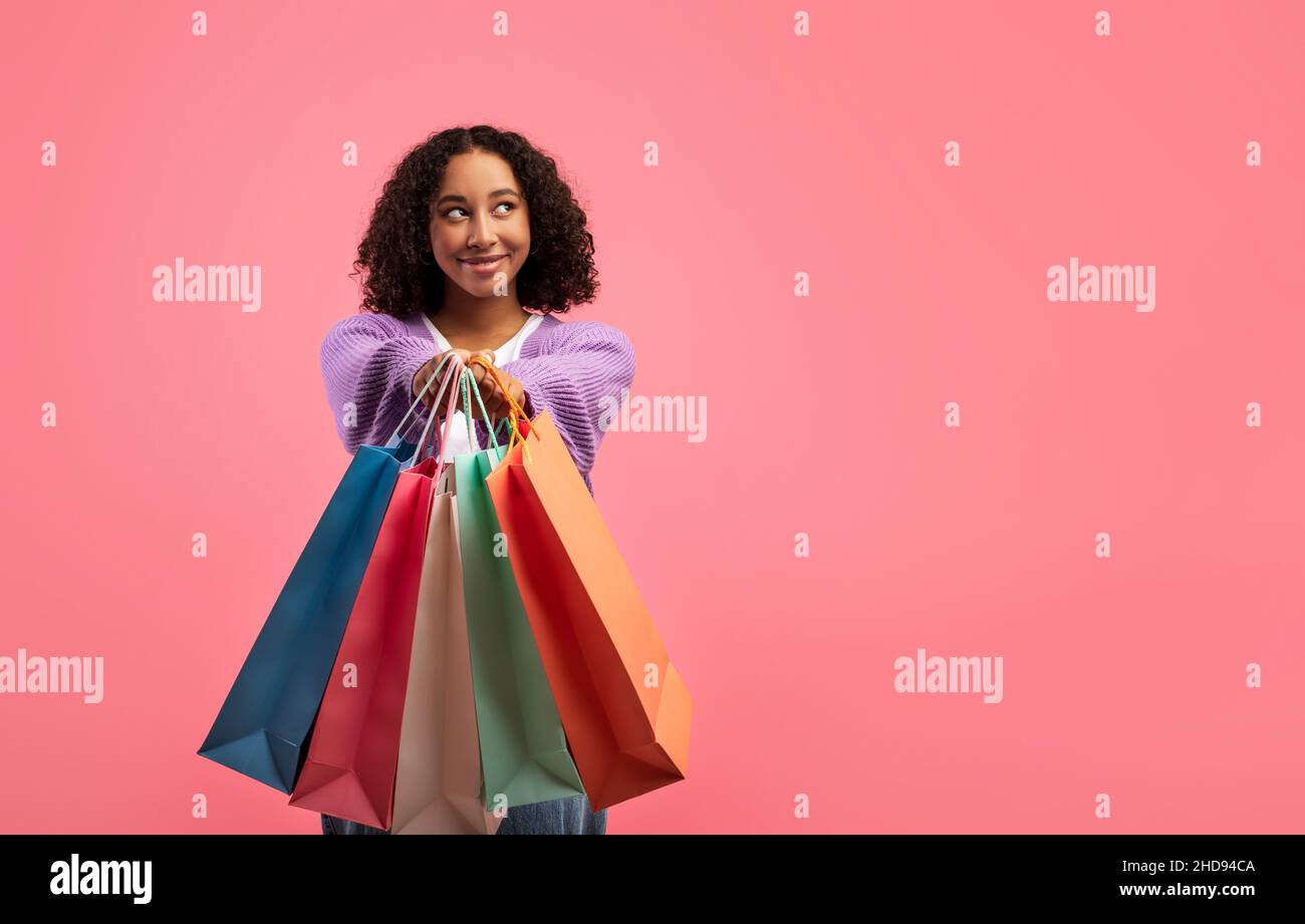 Cool shopping offer. Beautiful young black woman showing shopper bags ...