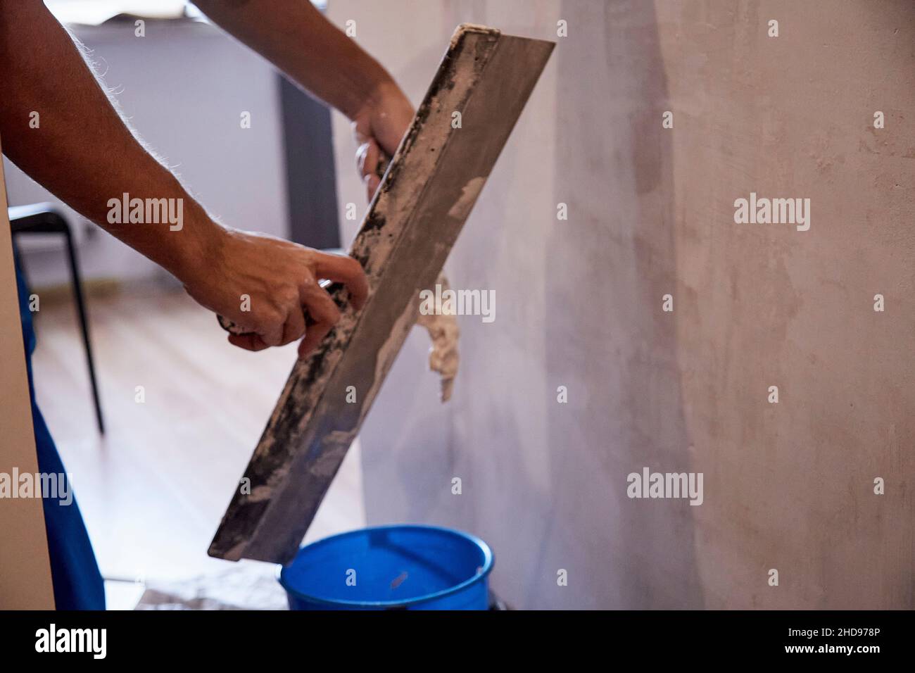 Home renovation: worker processes the wall with putty by work tool ...