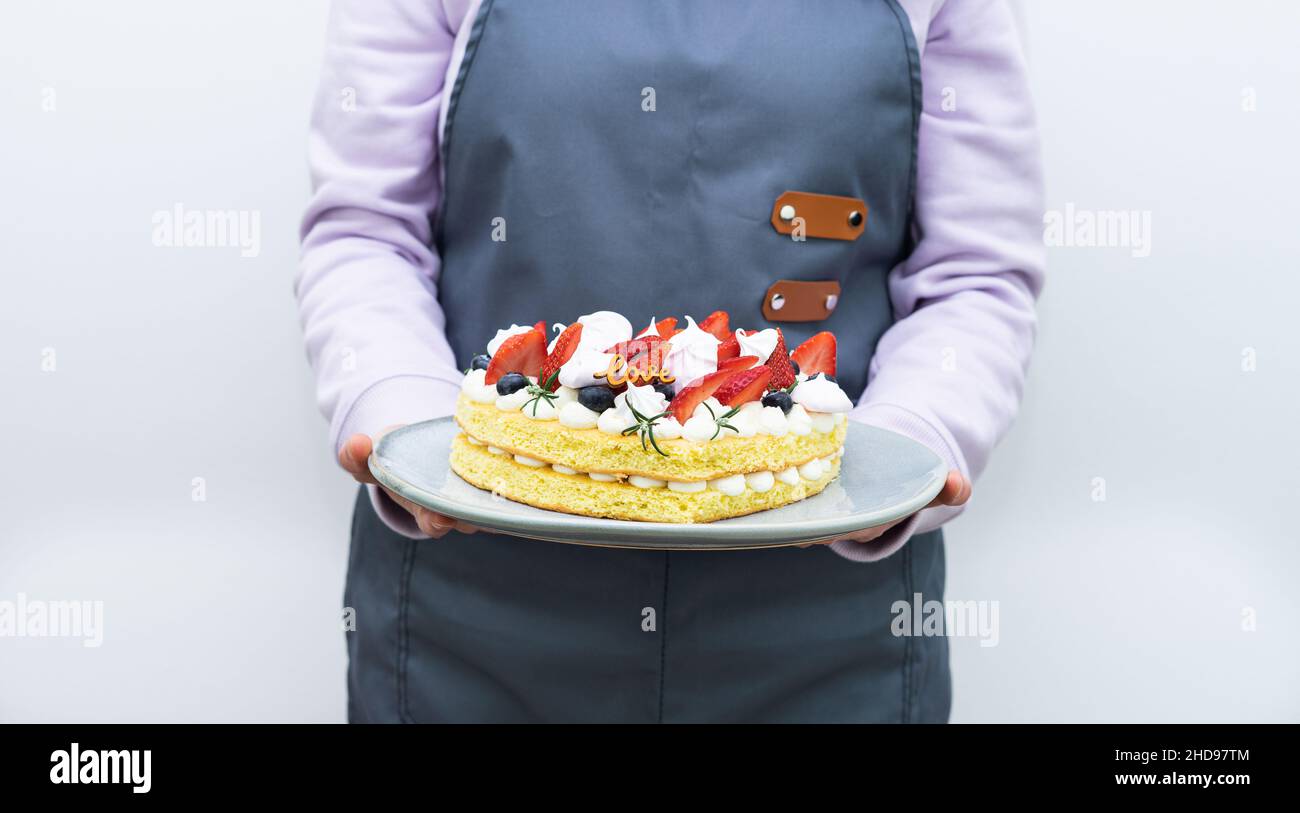 Woman waitress with heart-shaped cake decorated with red fruits and ...