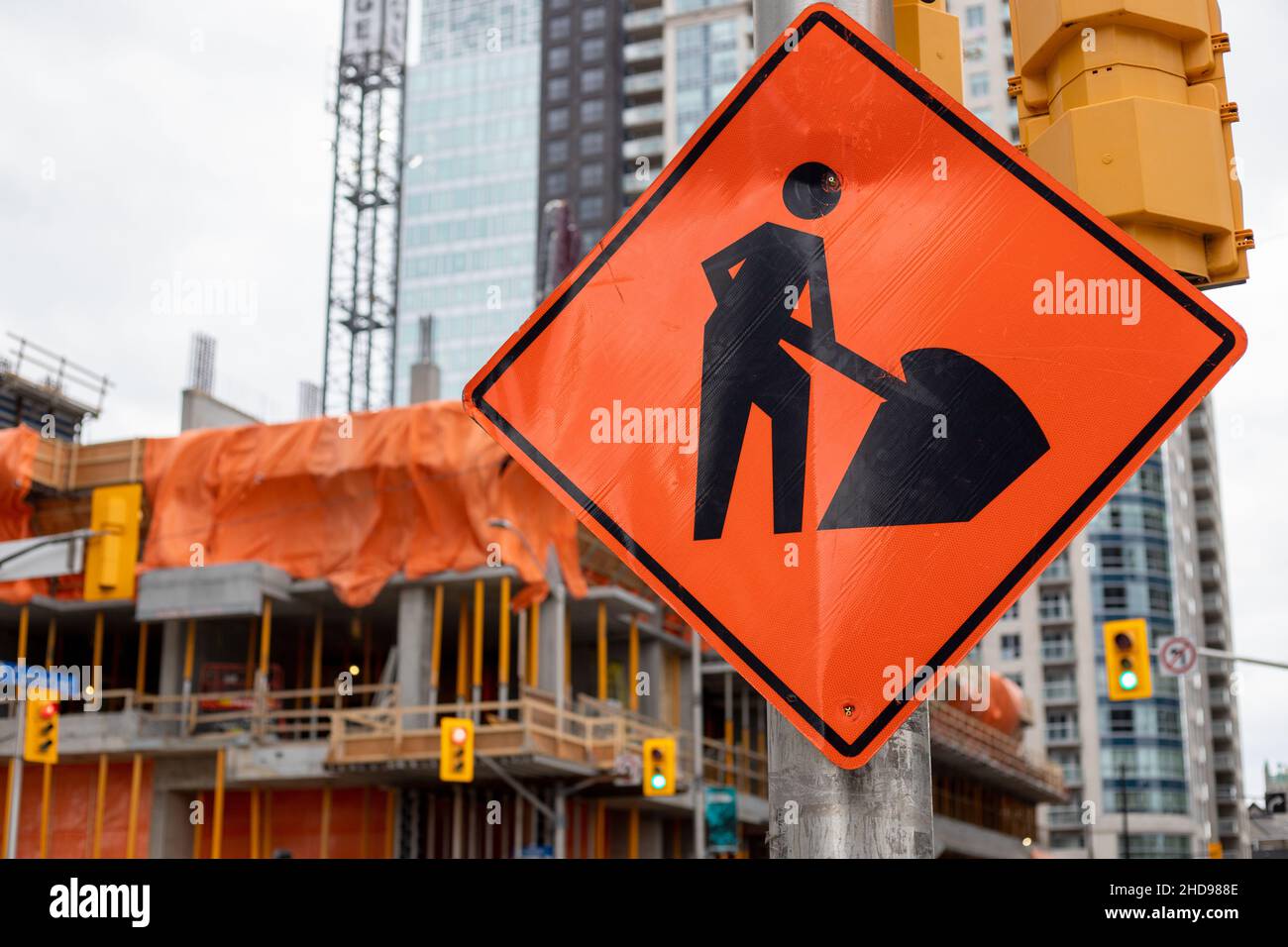 Construction orange road sign near construction site and buildings ...