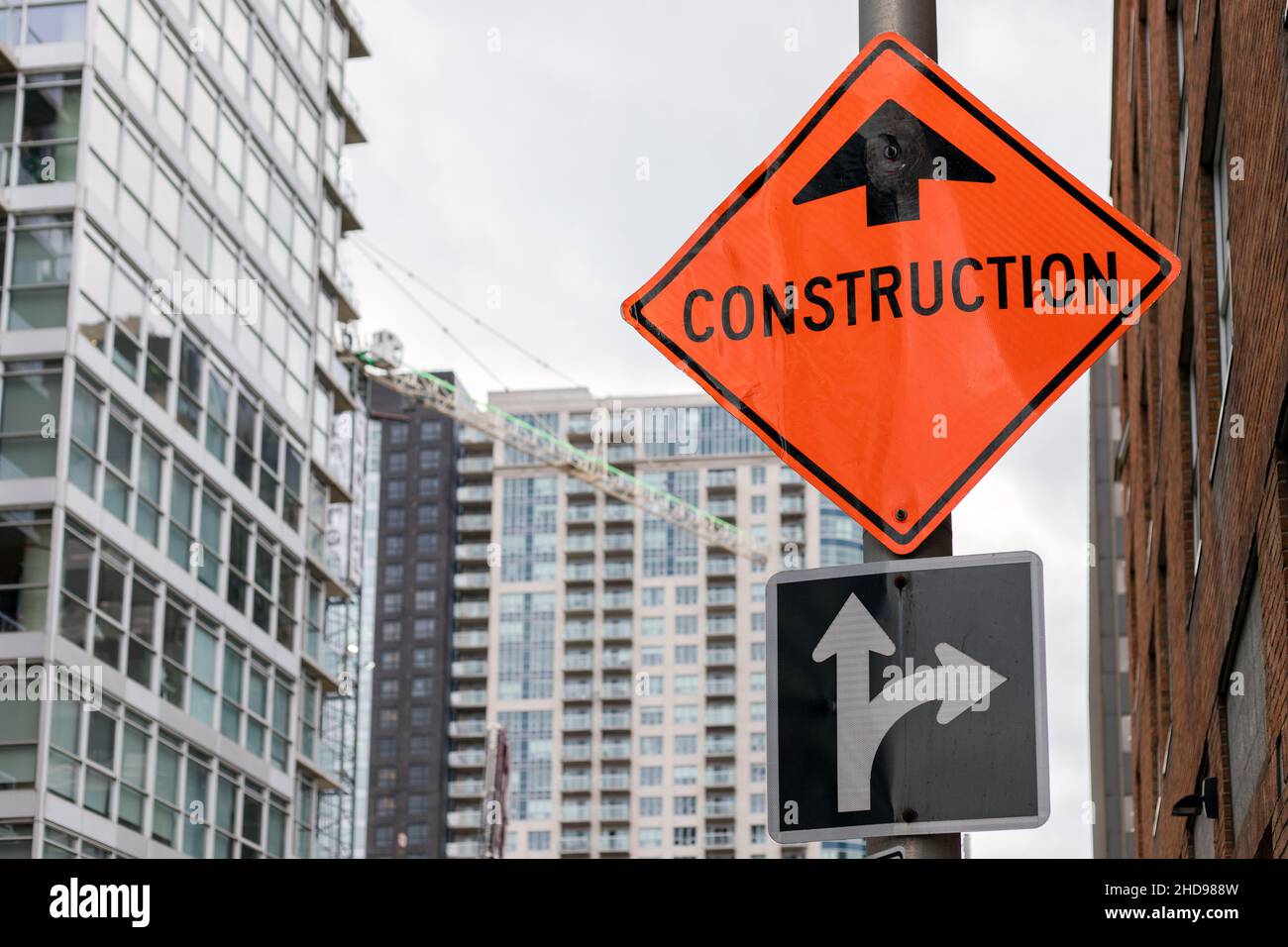 Construction orange sign near construction site against tall buildings ...