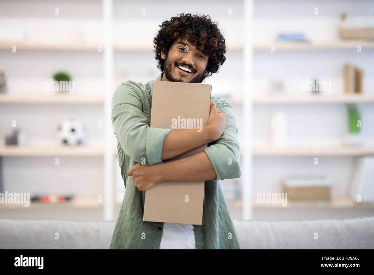 Happy young indian man hugging box a home Stock Photo - Alamy