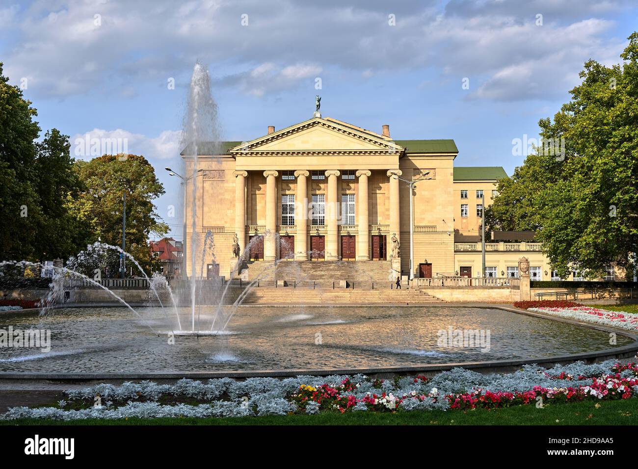 a fountain, flower beds and the facade of the historic opera house in ...