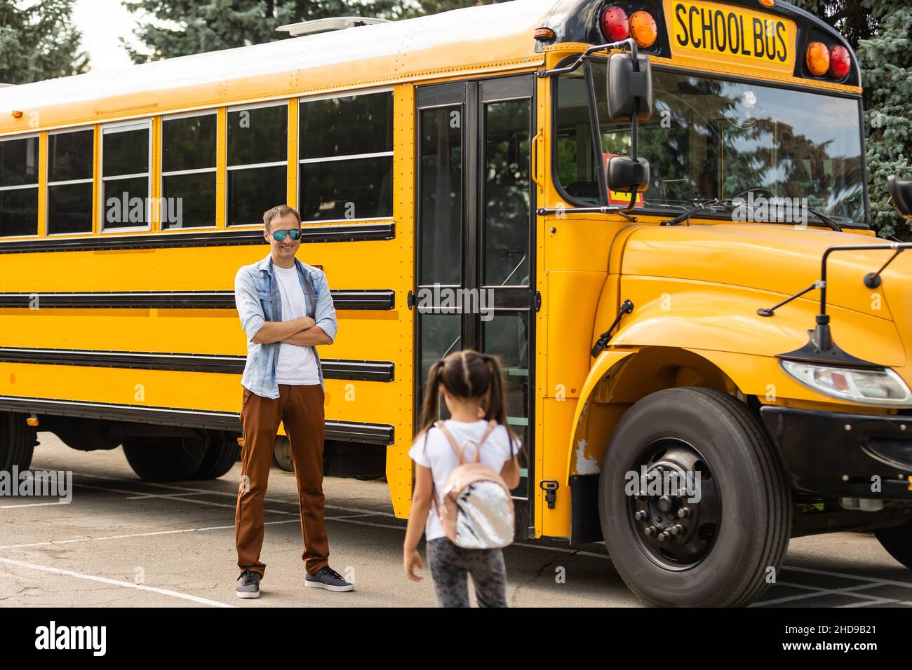 Smiling bus driver looking at camera outside the elementary school ...