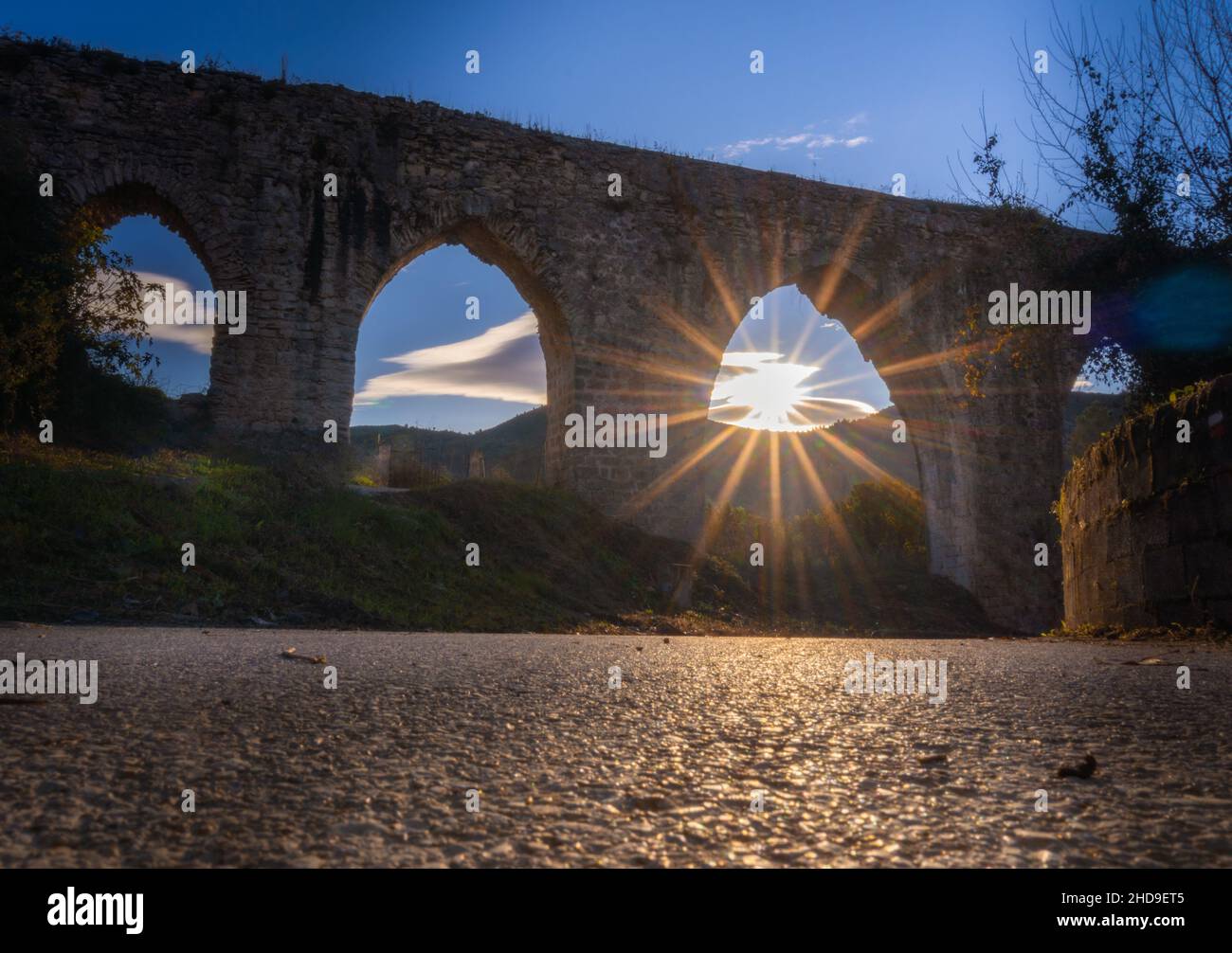 Low angle view of the rays of sun shinning through the arch of a bridge ...