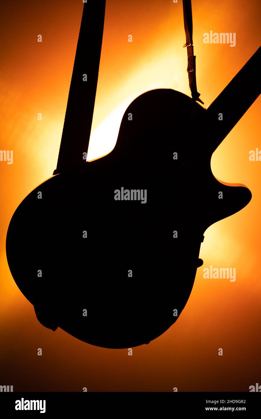 A vertical silhouette shot of an electric guitar on a yellow light ...