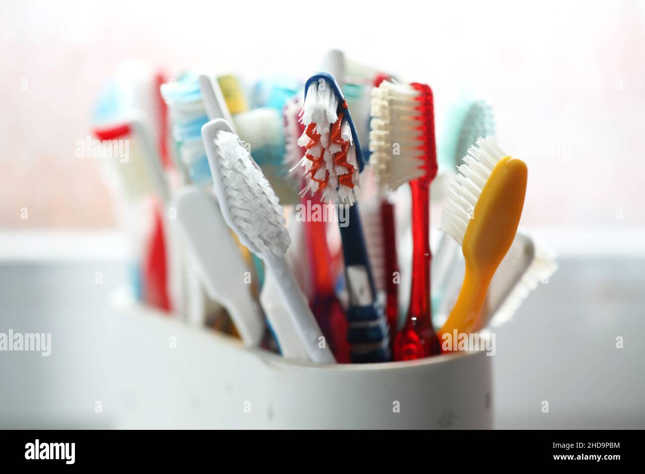 A selection of colourful plastic toothbrushes in a pot in a bathroom in ...