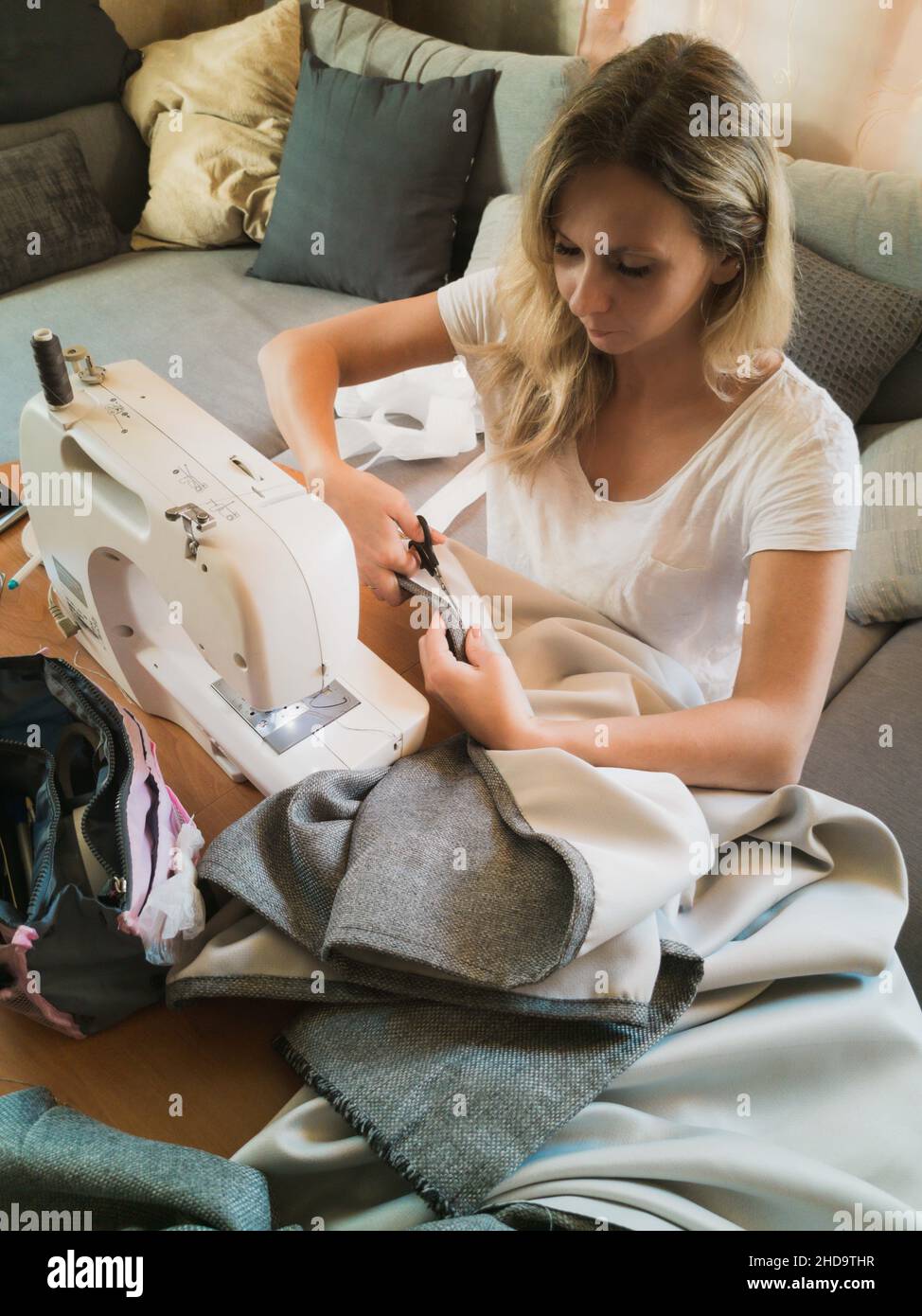 A beautiful, smiling young girl sewing on a sewing machine Stock Photo ...