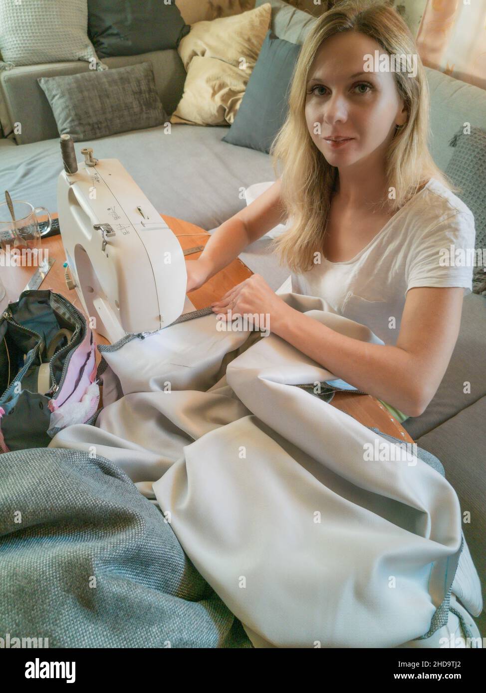 A beautiful, smiling young girl sewing on a sewing machine Stock Photo ...