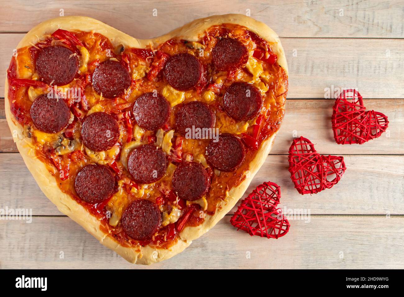 Heart shaped pepperoni pizza on a wooden background. Valentines day ...