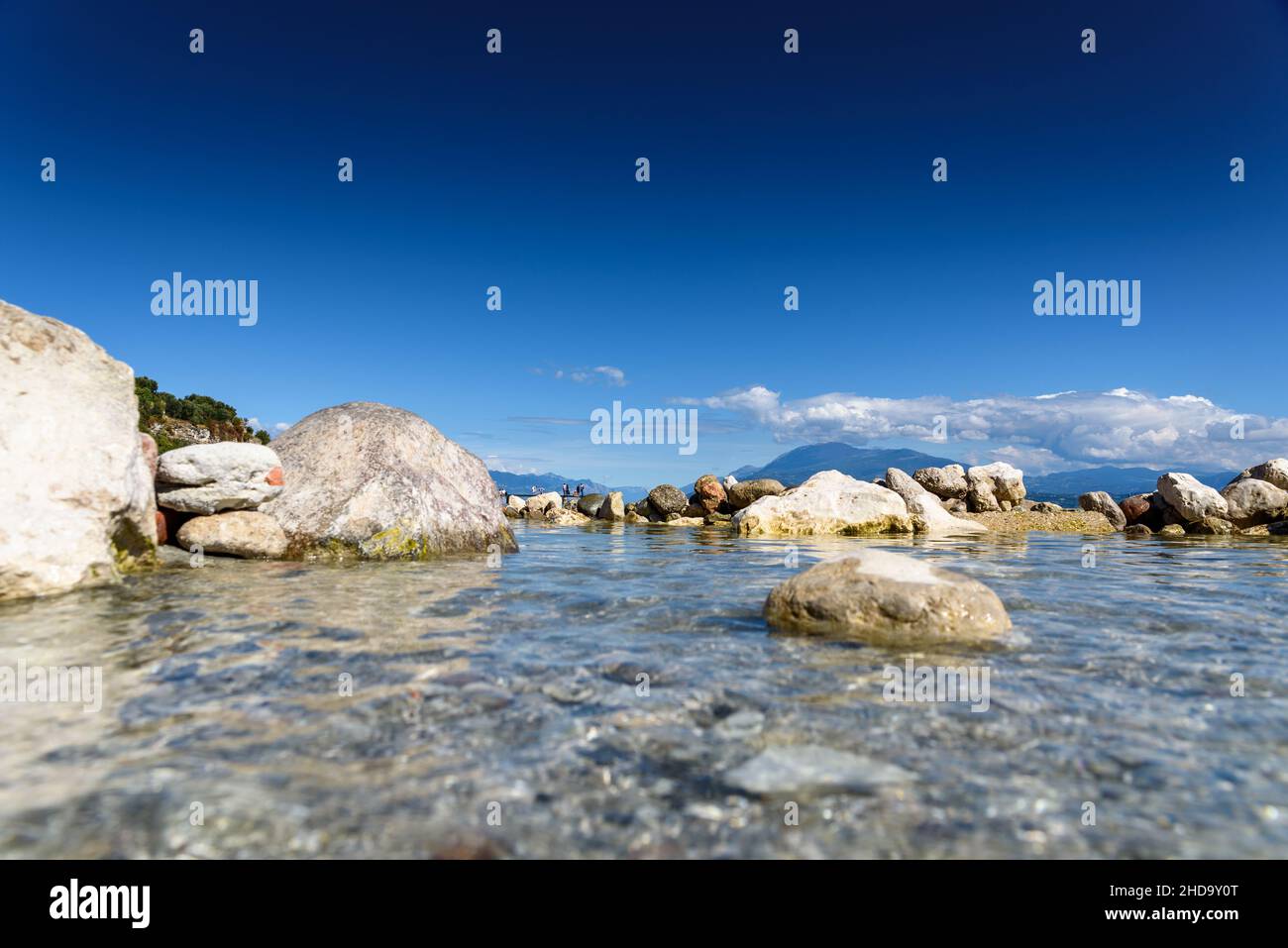The tide covers the rocks on the shore of a crystal clear lake Stock ...