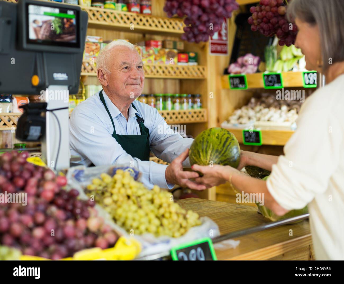 Senior cashier serving customer in greengrocer Stock Photo - Alamy