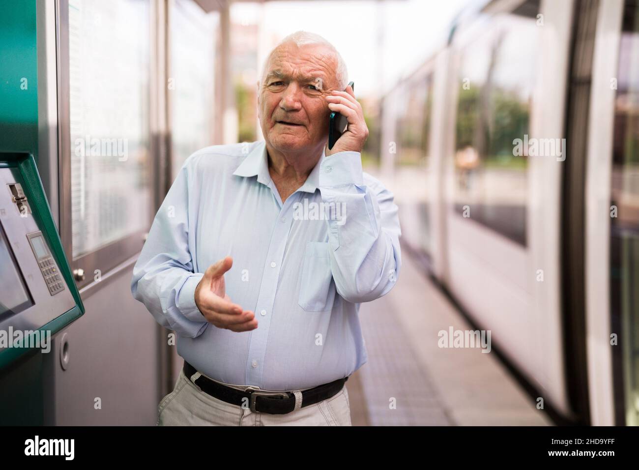 Old man talking on phone in tram station Stock Photo - Alamy