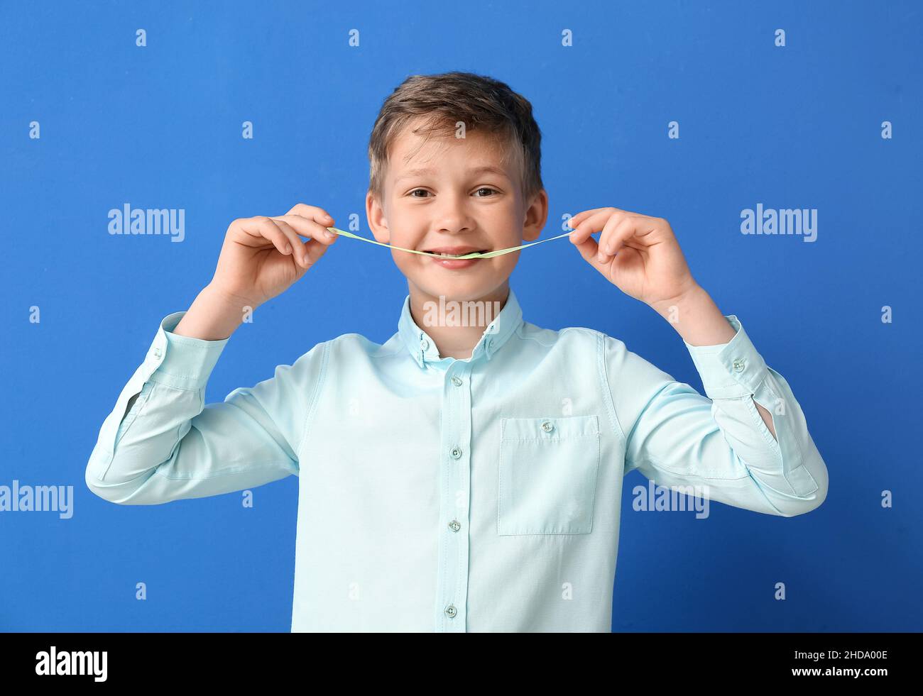 Cute little boy chewing gum on blue background Stock Photo - Alamy