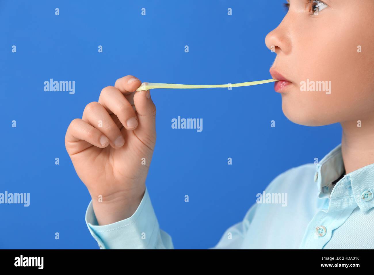 Cute little boy chewing gum on blue background Stock Photo - Alamy