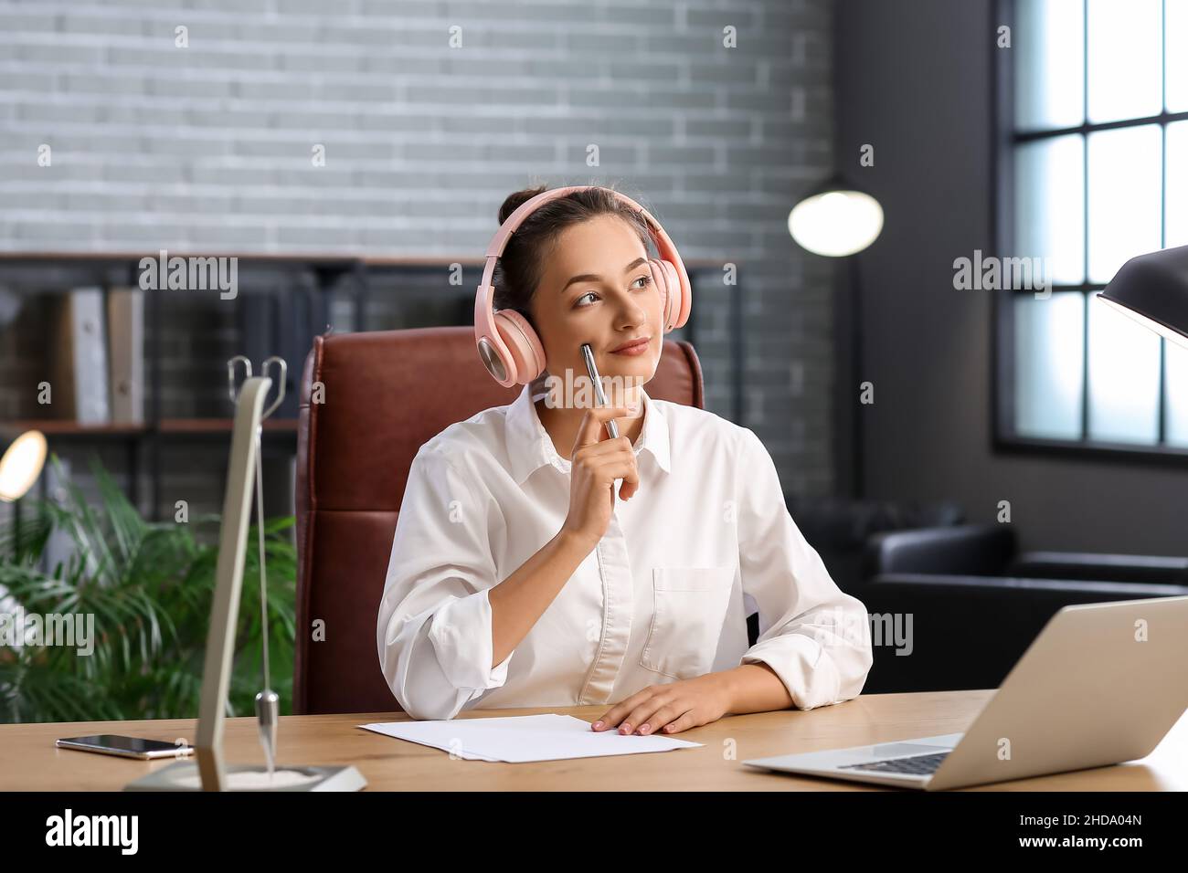 Pretty young woman listening to music while working in office Stock ...
