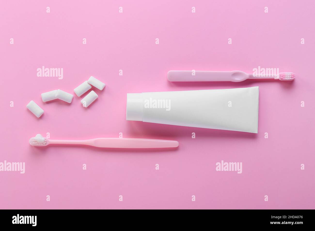 Tube with tooth paste, brushes and tasty chewing gums on pink ...