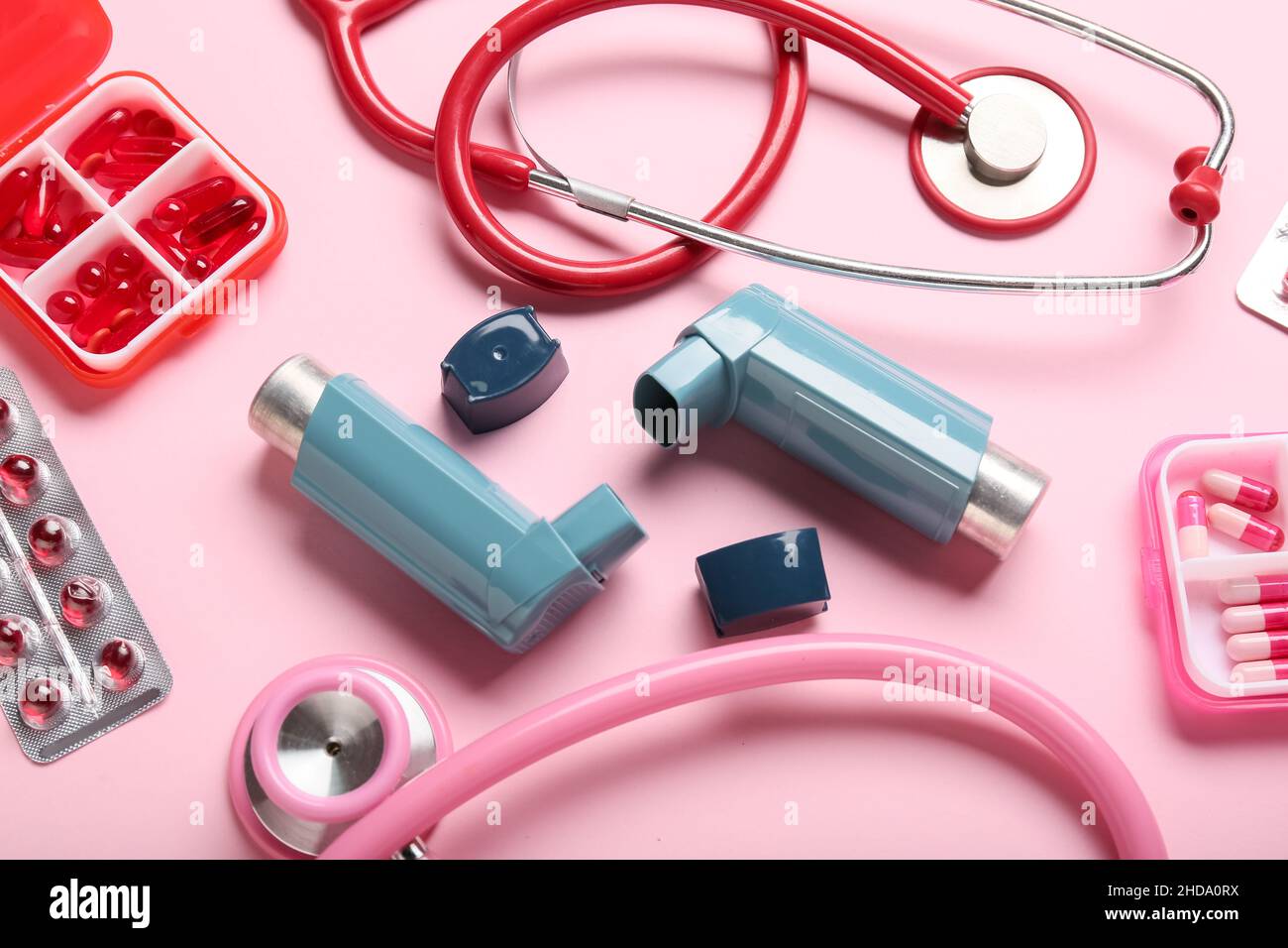 Asthma inhalers, stethoscopes and pills on pink background, closeup ...