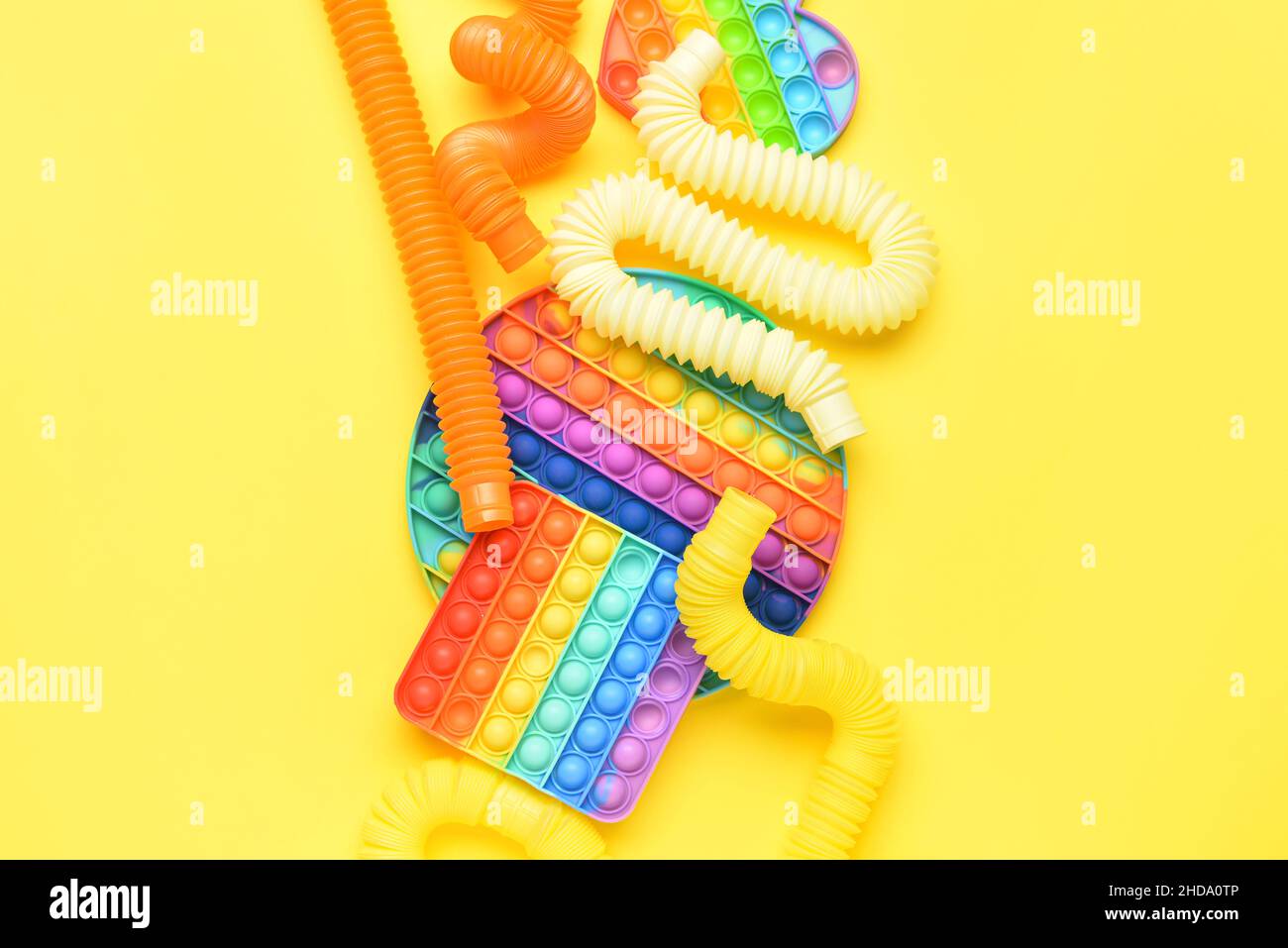 Colorful Pop Tubes and Pop it fidget toys on yellow background Stock ...