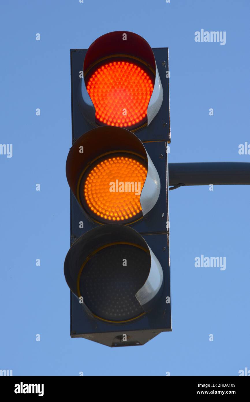 Yellow traffic light on a horizontal white metal beam, isolated on sky ...