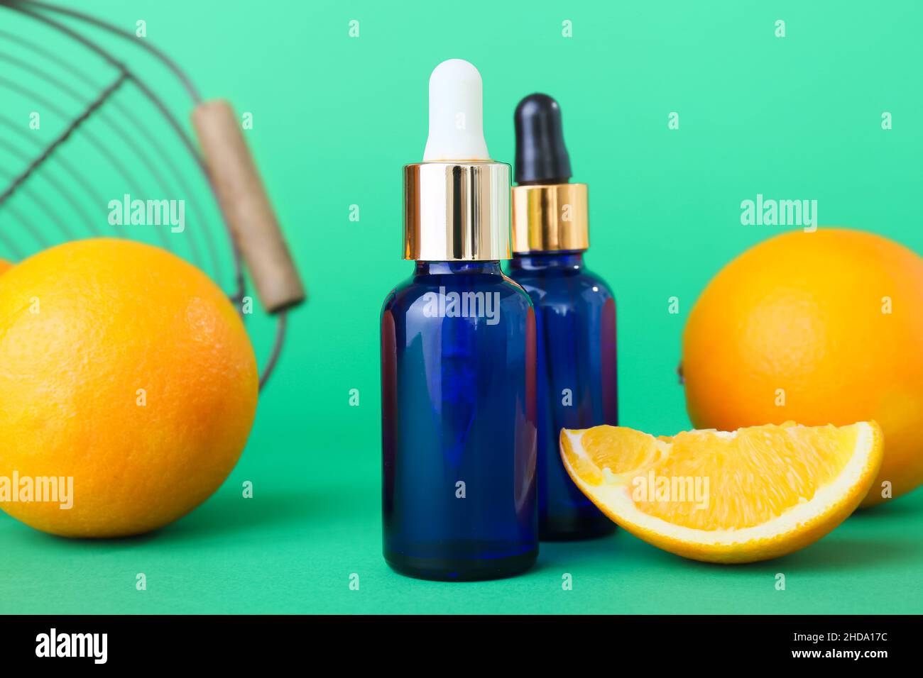 Bottles of essential oil and fresh oranges on green background Stock ...
