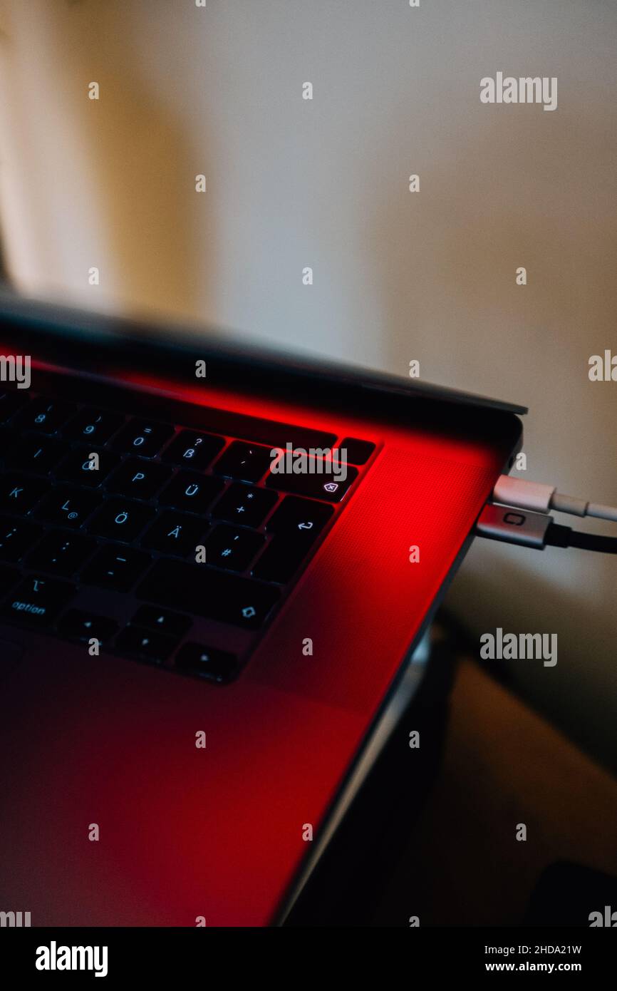 Closeup shot of the keyboard of laptop with cables sockets plugged in ...