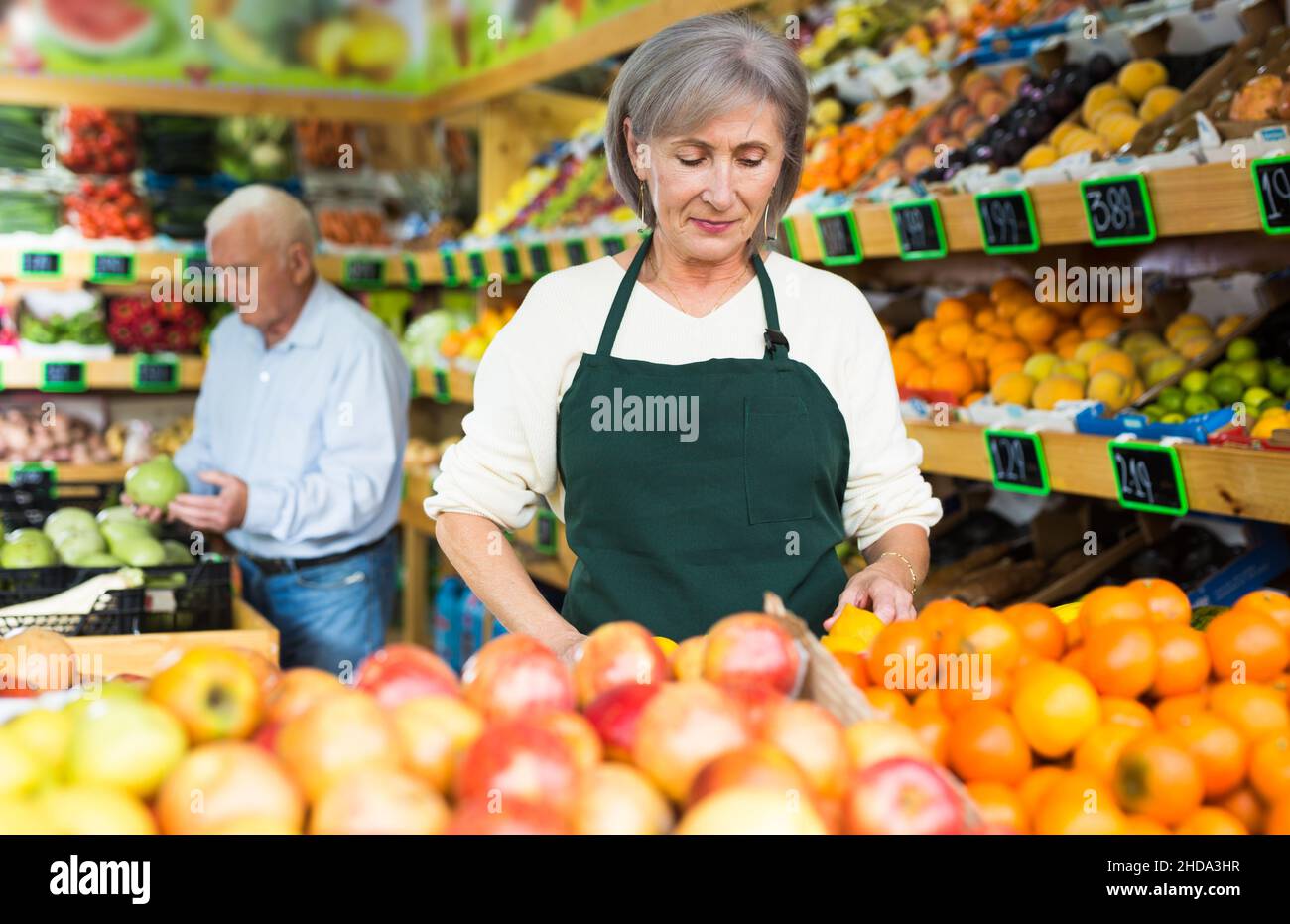 Female supermarket worker stacking fruits on shelf in sales room Stock ...