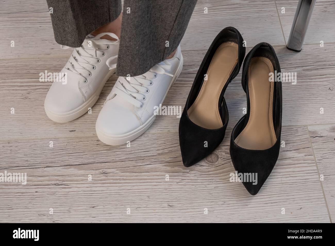 Close-up business woman takes off her shoes puts on white leather ...