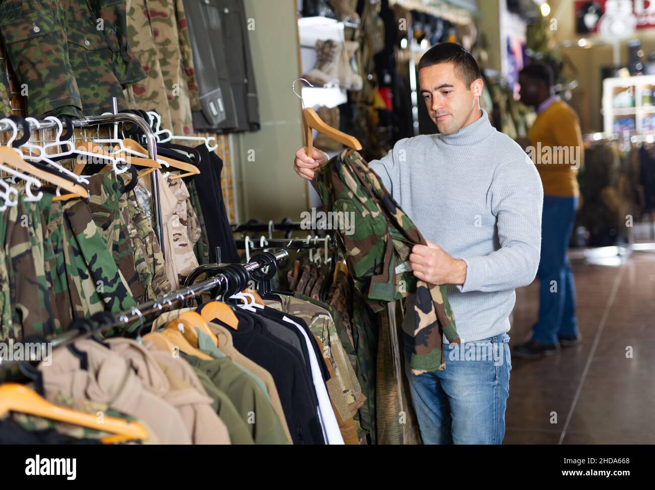 Man chooses camouflage uniform at army store Stock Photo - Alamy