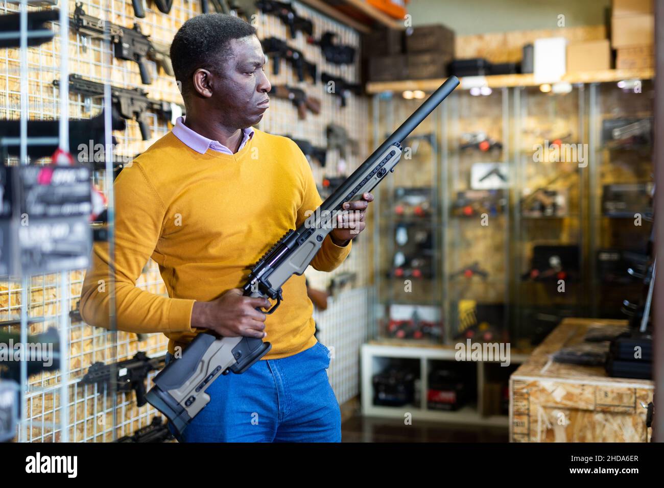 Man choosing hunting rifle in weapon shop Stock Photo - Alamy